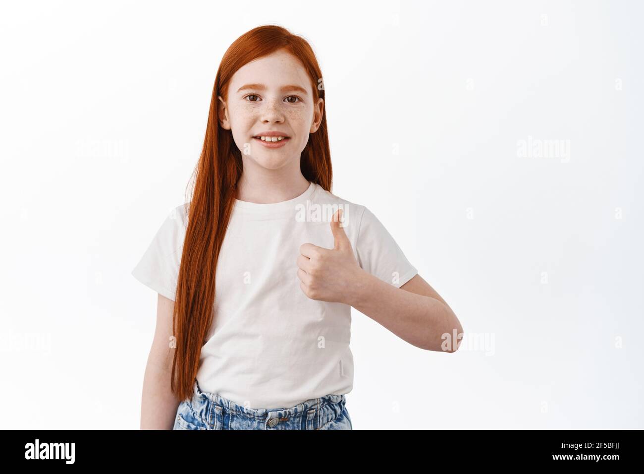 Little child girl with long ginger hair, redhead kid shows thumbs up ...
