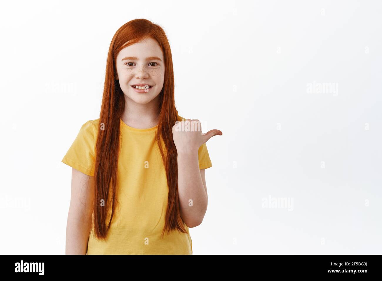 Happy cute little redhead child pointing finger aside. Ginger girl with ...