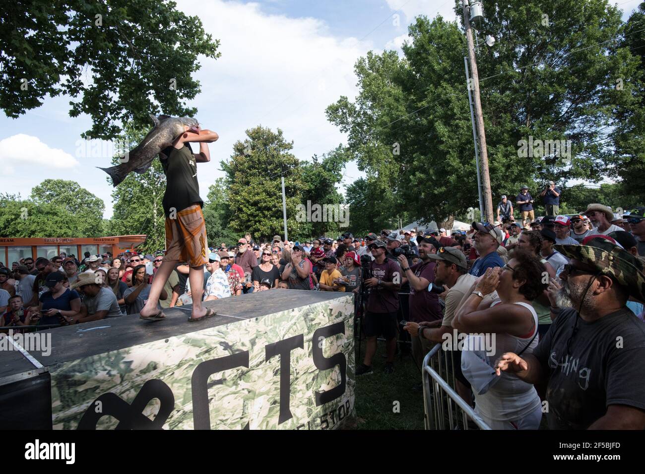 A triumphant noodler proudly displays his catfish to a cheering crowd ...