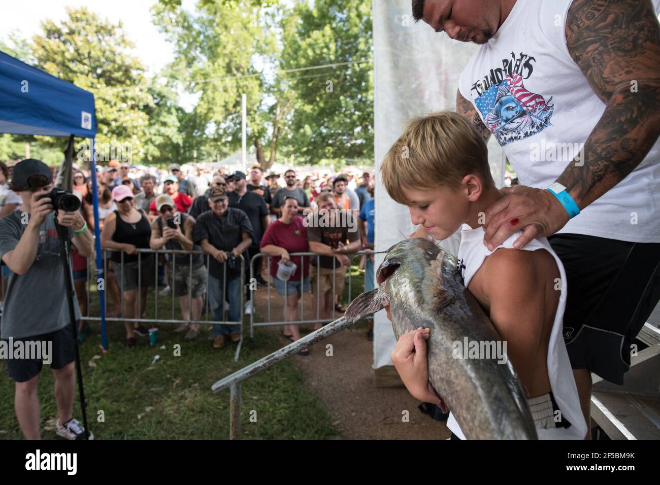 A triumphant noodler proudly displays his catfish to a cheering crowd ...
