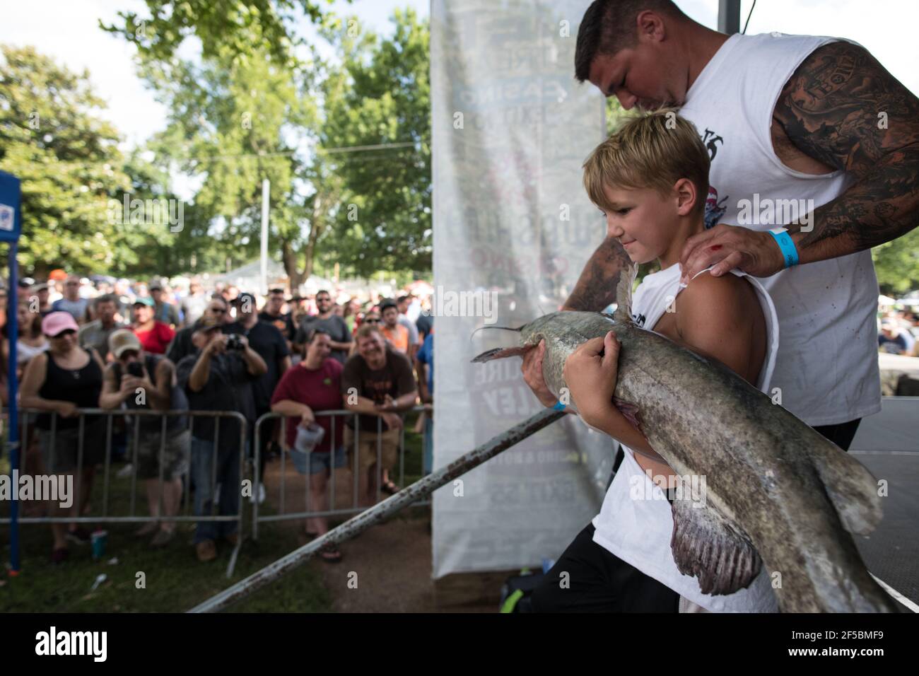 A triumphant noodler proudly displays his catfish to a cheering crowd ...