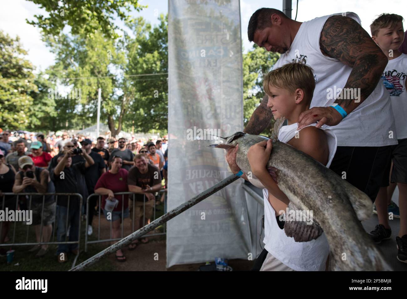 A triumphant noodler proudly displays his catfish to a cheering crowd ...