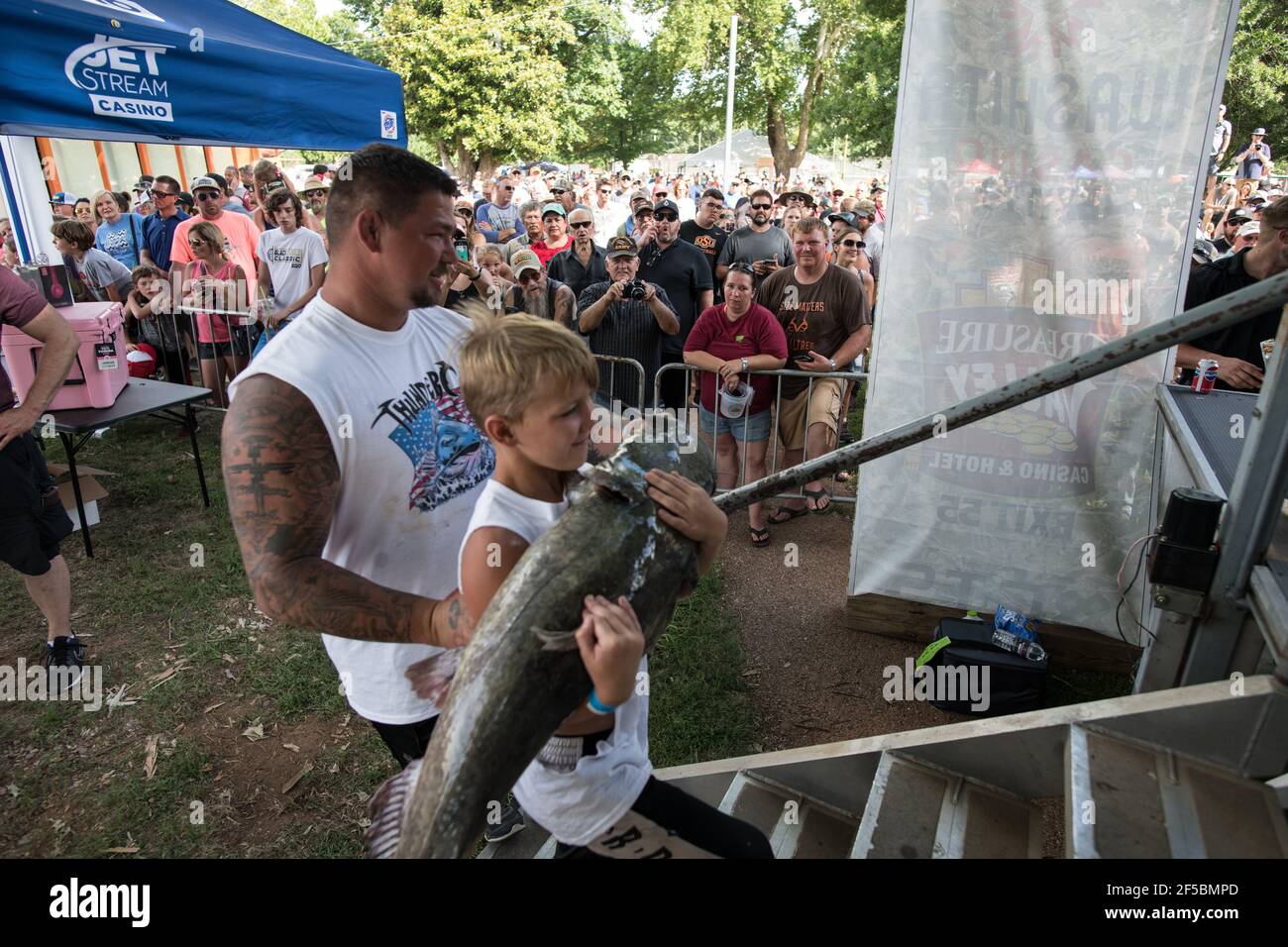 A triumphant noodler proudly displays his catfish to a cheering crowd ...