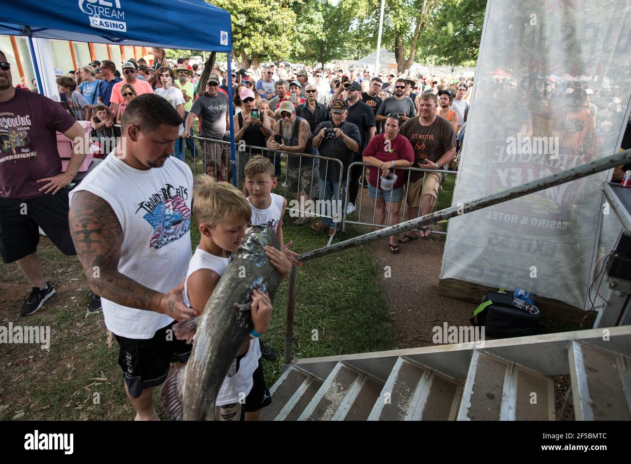 A triumphant noodler proudly displays his catfish to a cheering crowd ...
