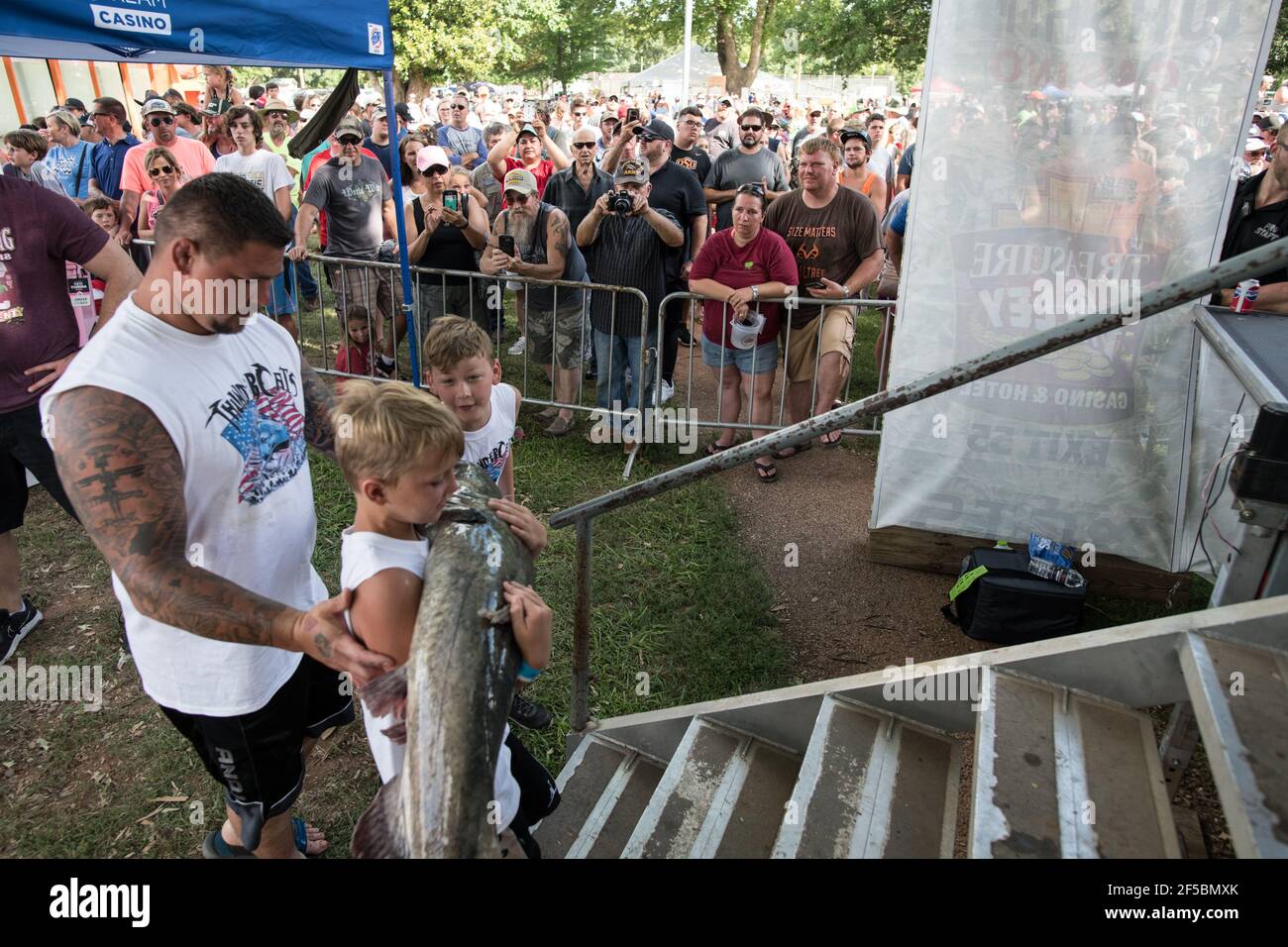 A triumphant noodler proudly displays his catfish to a cheering crowd ...