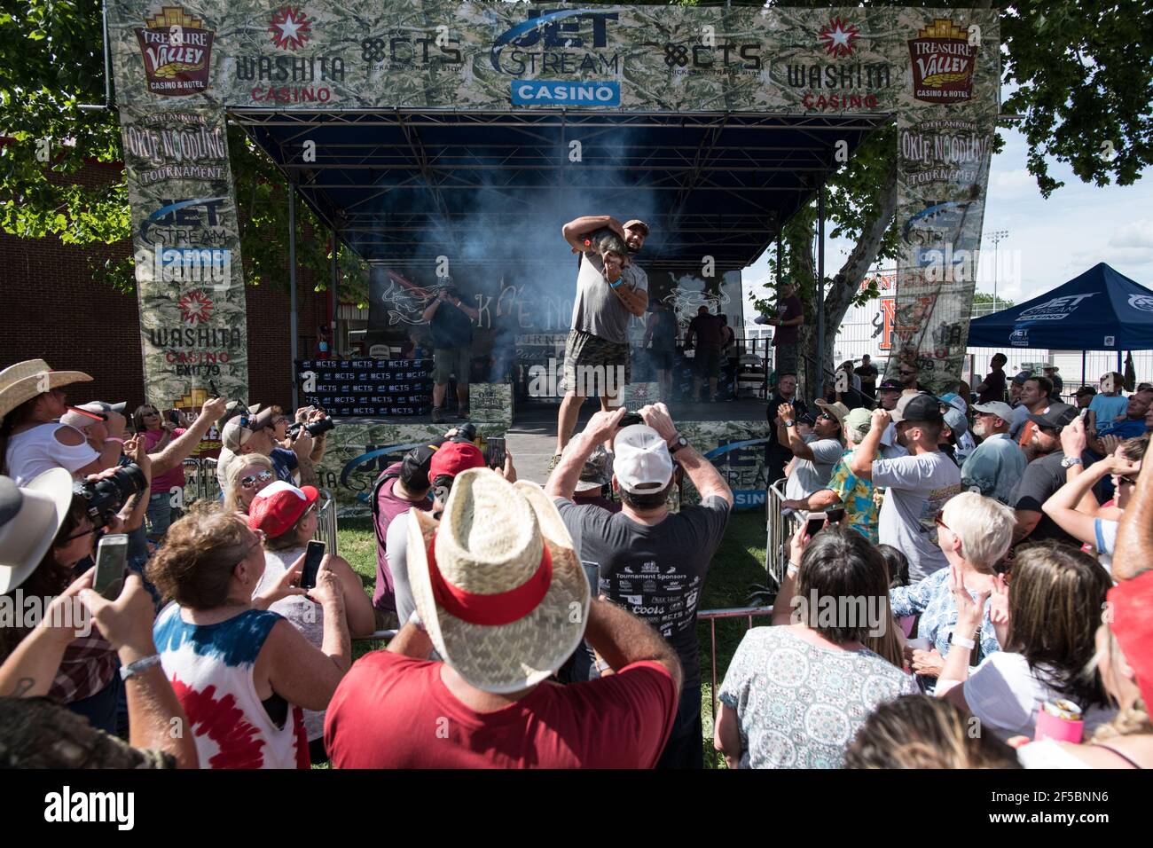 A triumphant noodler proudly displays his catfish to a cheering crowd ...