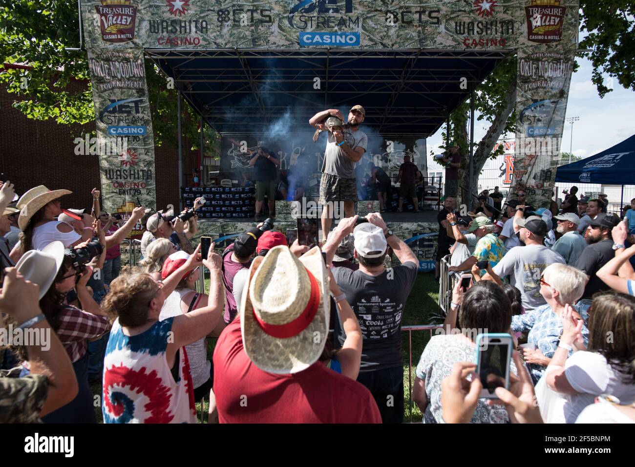 A triumphant noodler proudly displays his catfish to a cheering crowd ...