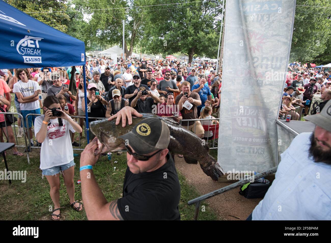 A triumphant noodler proudly displays his catfish to a cheering crowd ...