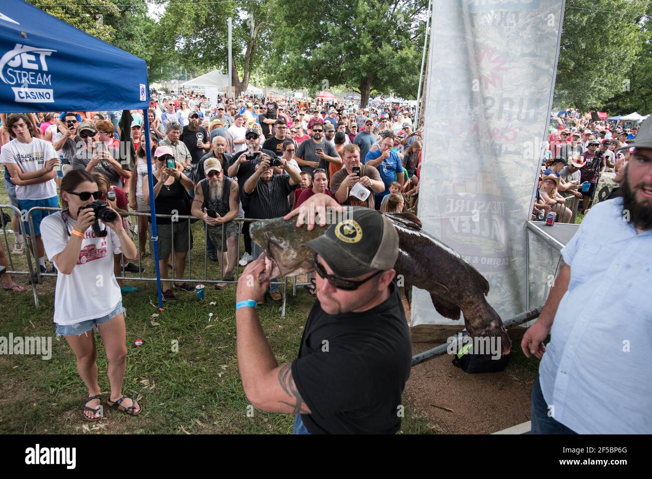 A triumphant noodler proudly displays his catfish to a cheering crowd ...