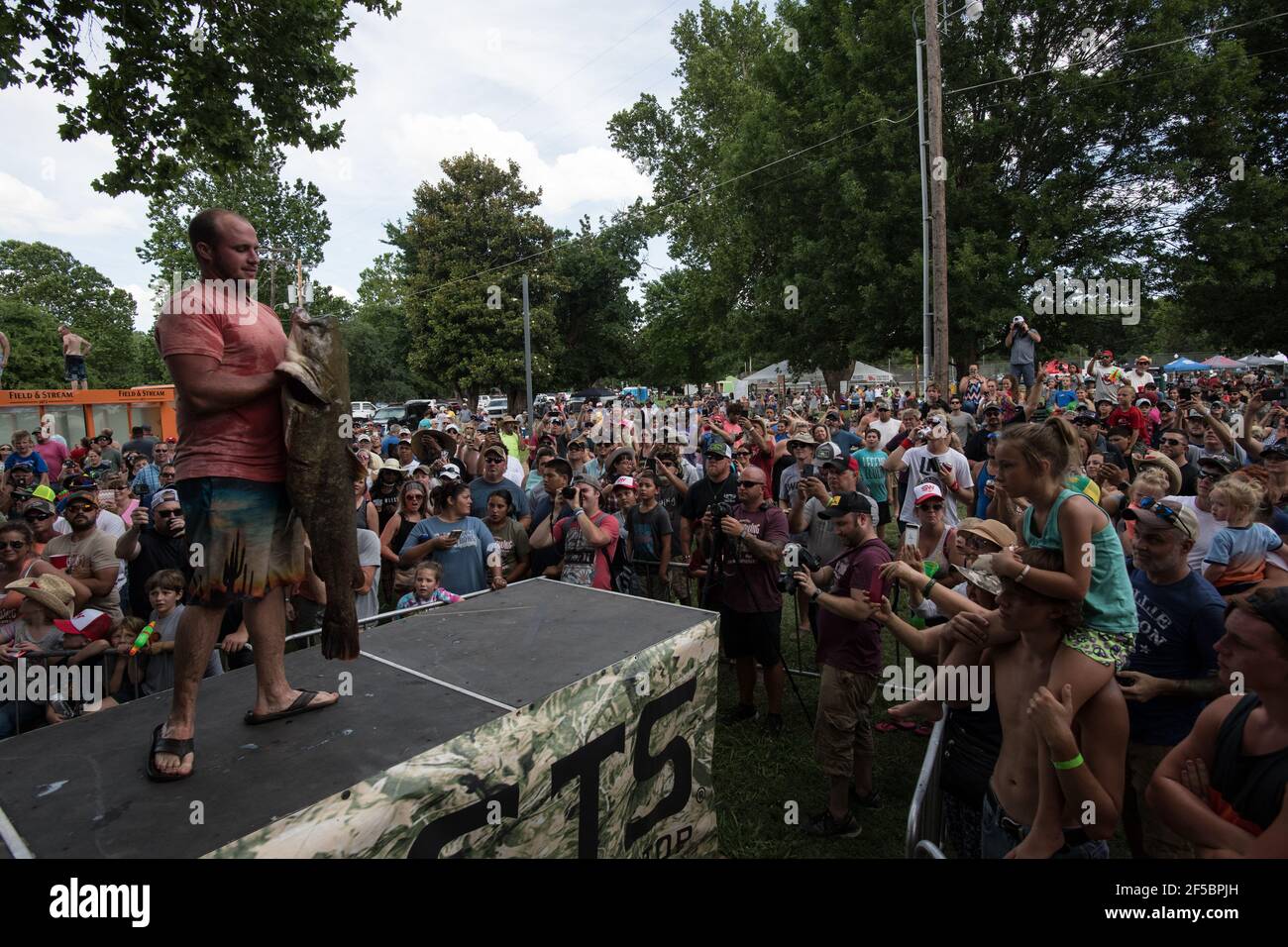 A triumphant noodler proudly displays his catfish to a cheering crowd ...