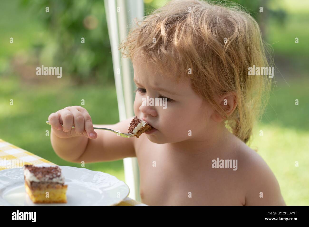 Baby eating cake. Cute little boy eat sweets. The blond boy is eating a ...