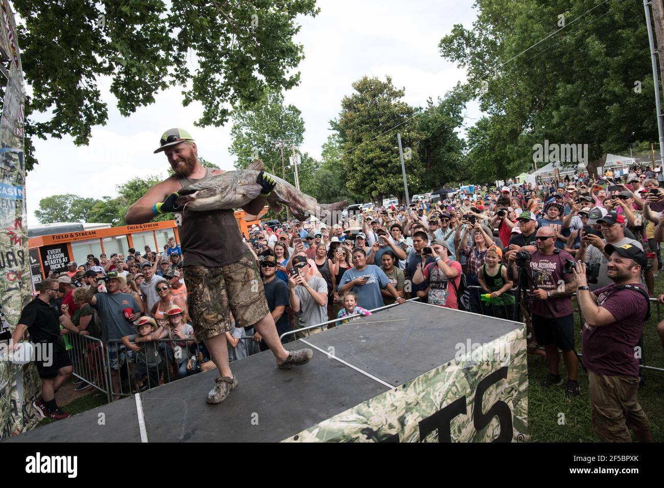 A triumphant noodler proudly displays his catfish to a cheering crowd ...