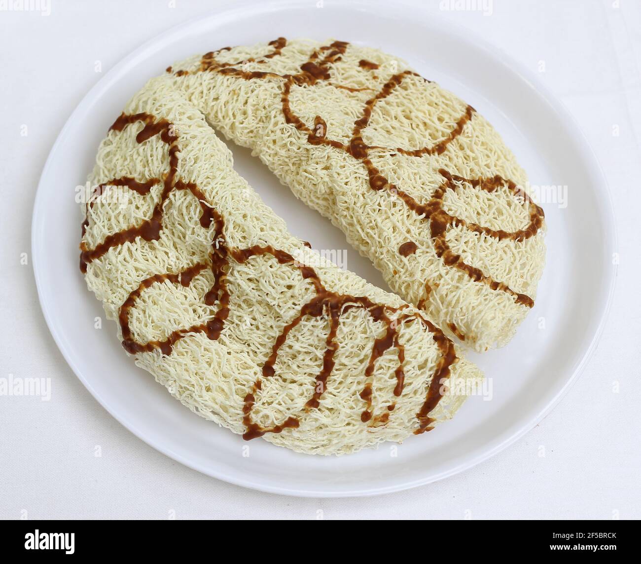 Two Aasmi on white plate,Aasmi is a Sri Lankan deep fried sweet snack ...