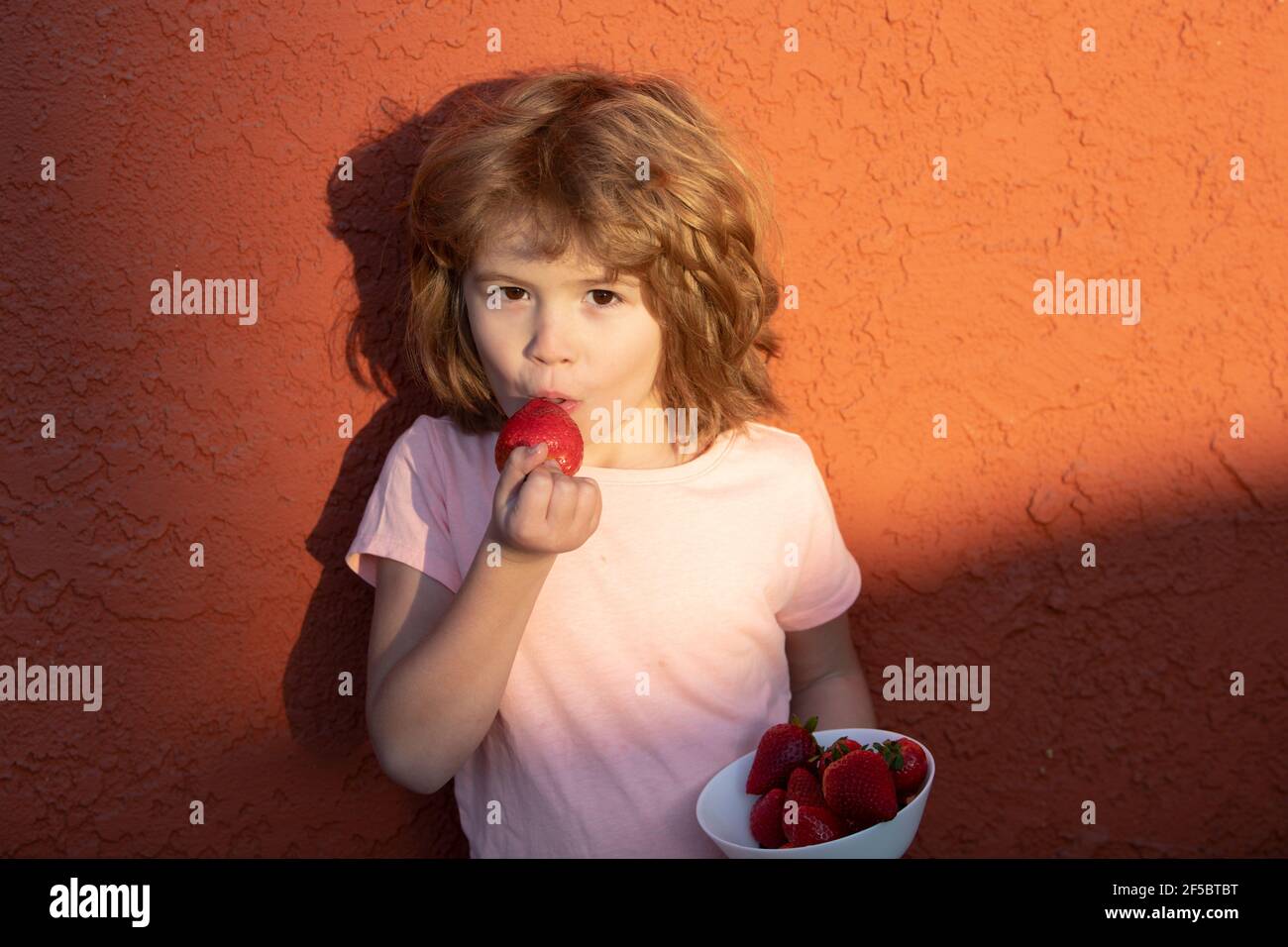 Child eating strawberries. Cute kid holding a strawberry Stock Photo ...