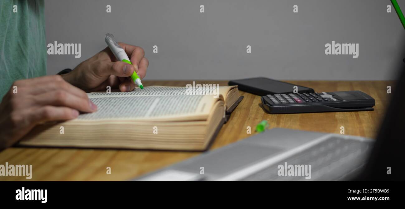 panoramic photo of a person hand underlining a book, with a green ...