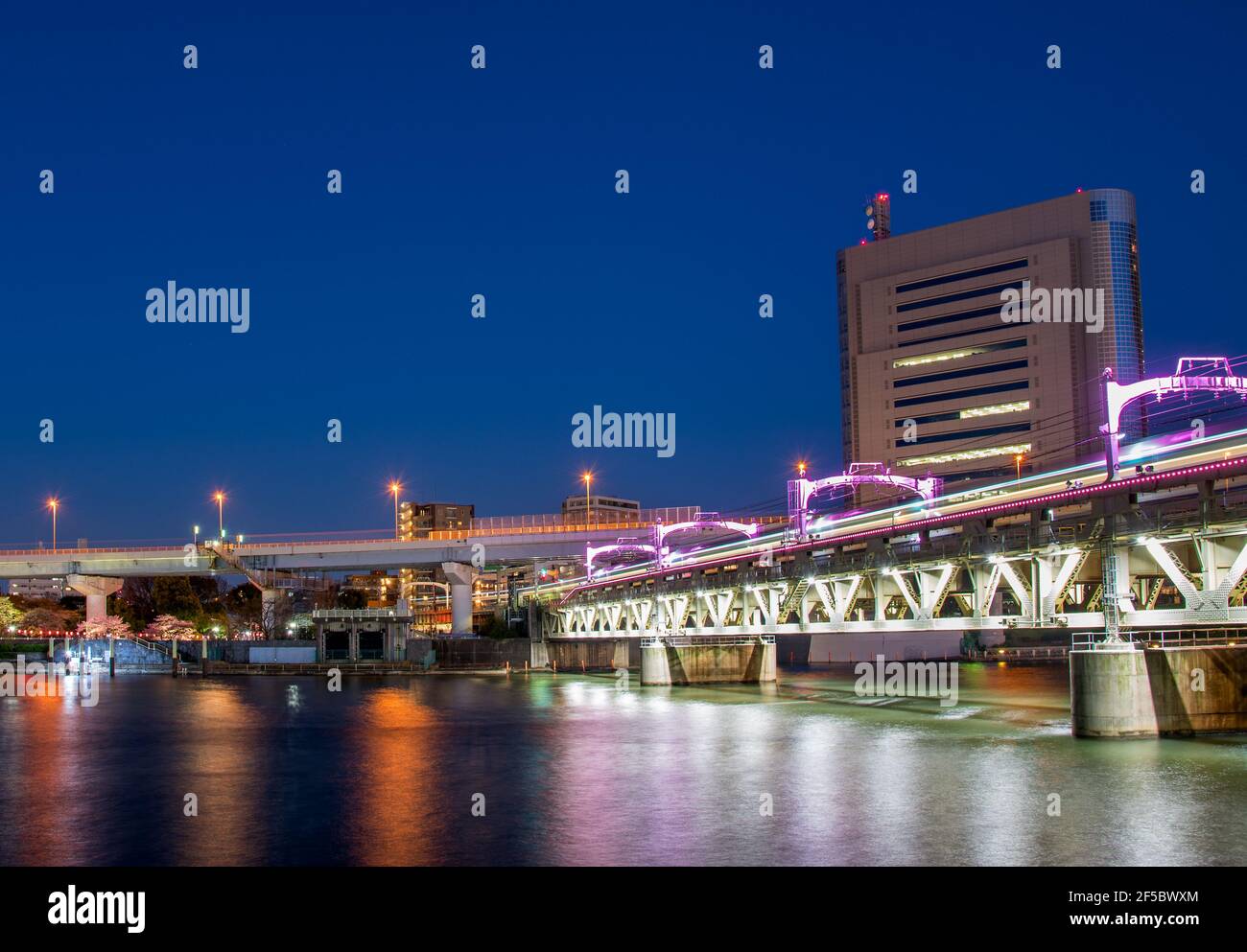 Speed train crossing an illuminated bridge spanning a mighty river ...