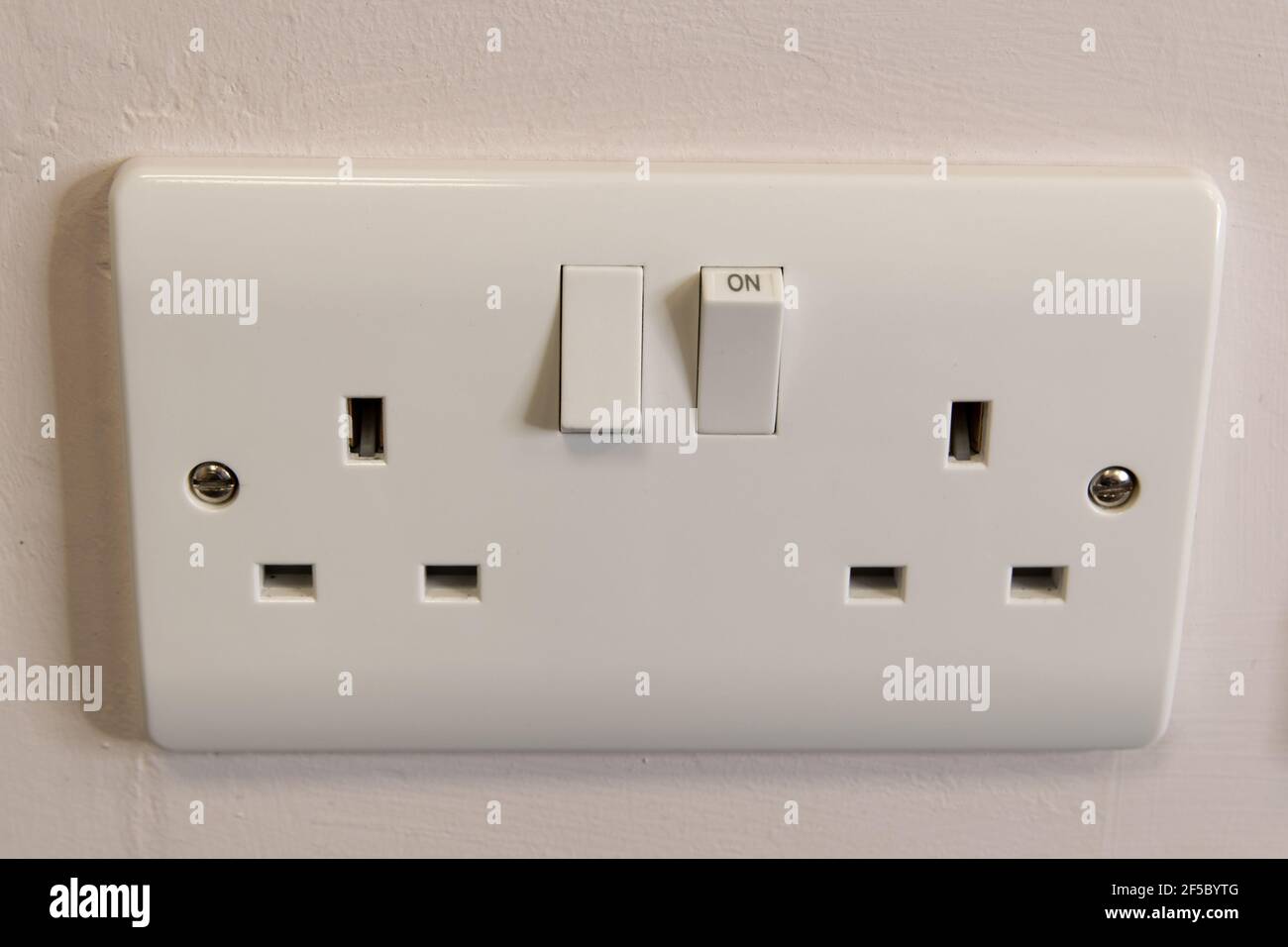 Two British white power sockets. One socket turned on and the other off ...