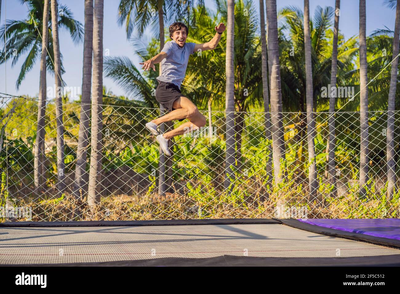 Happy man jumping on an outdoor trampoline, against the backdrop of ...