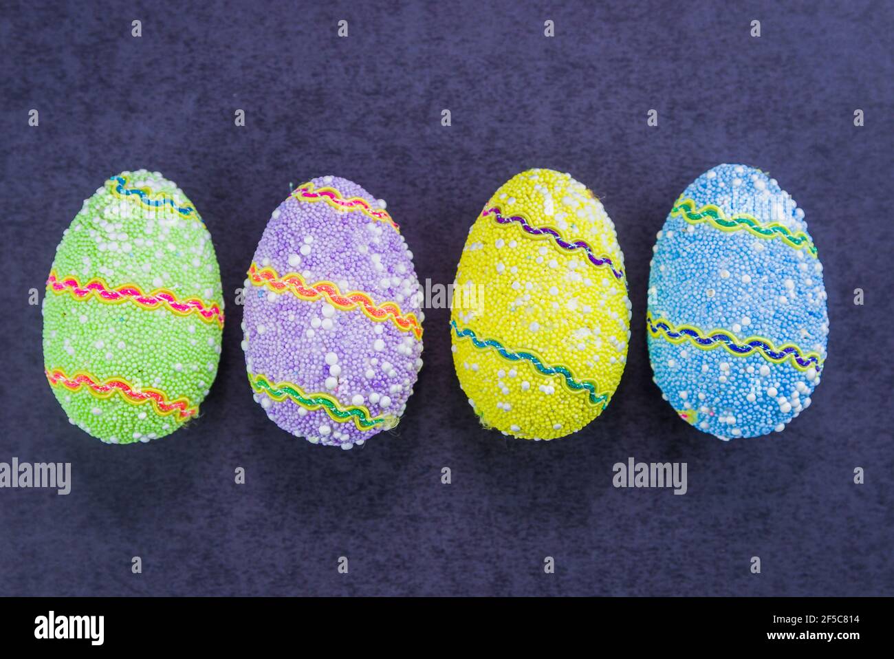 Colorful Easter eggs lined up side by side on a trendy black background ...