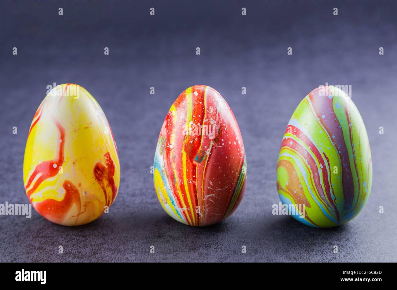 Colorful Easter eggs lined up side by side on a trendy black background ...