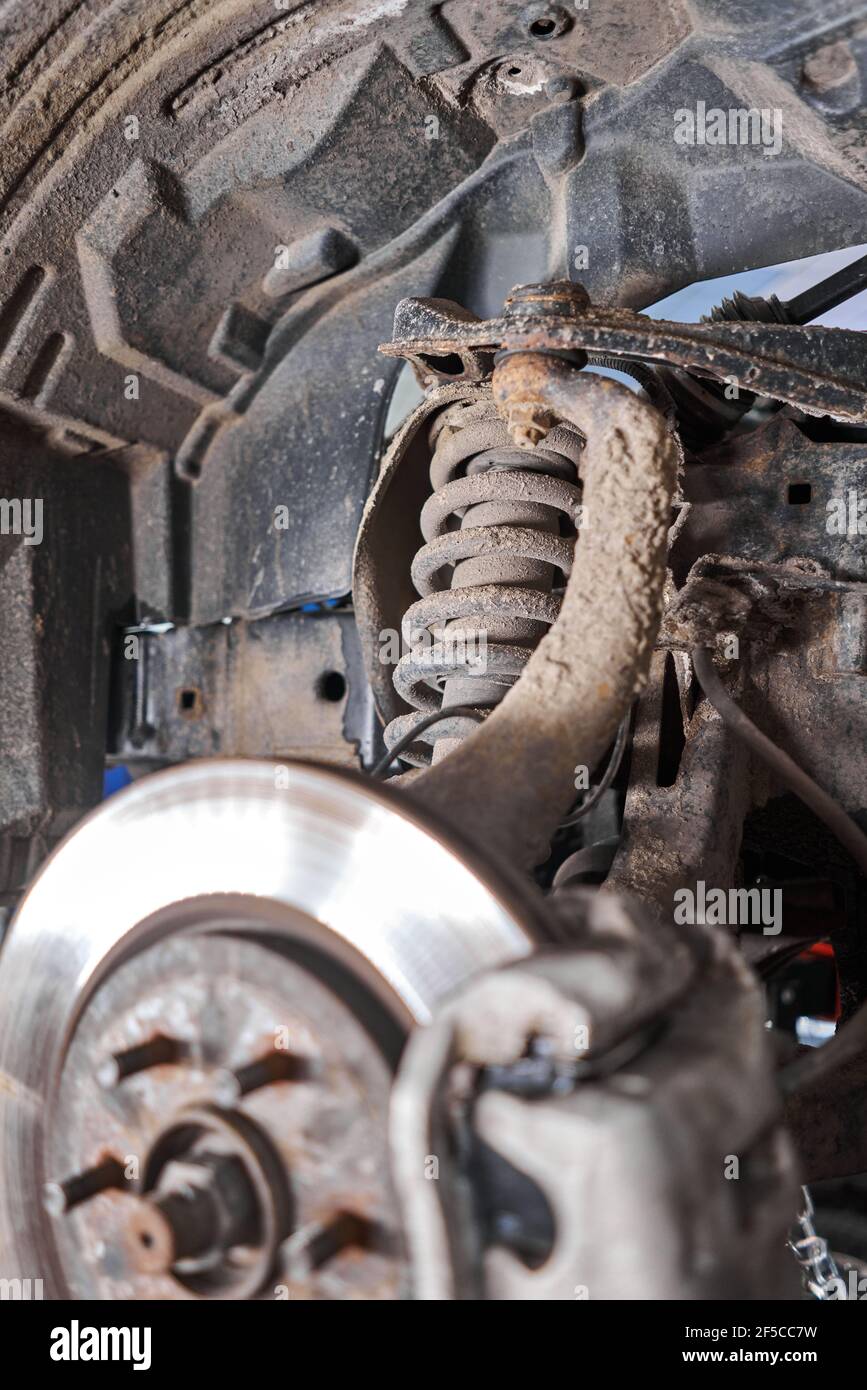 Inspects shock absorber, springs and stabilizer bars with a flashlight ...