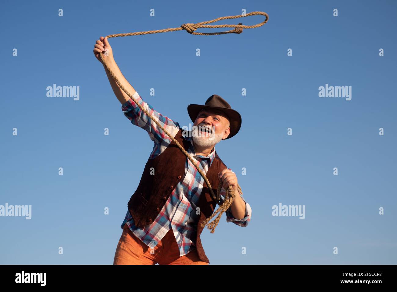 Old wild west cowboy at rodeo. Western pensioner with lasso rope ...