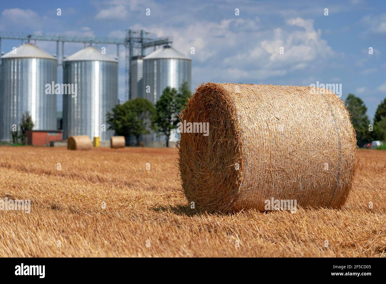 Hay Bales and Grain Silos in a Field Against Blue Sky With White Clouds ...