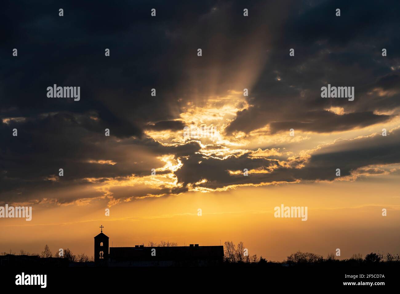 Dramatic orange sunset like fire in the sky with dark clouds. Rays of ...
