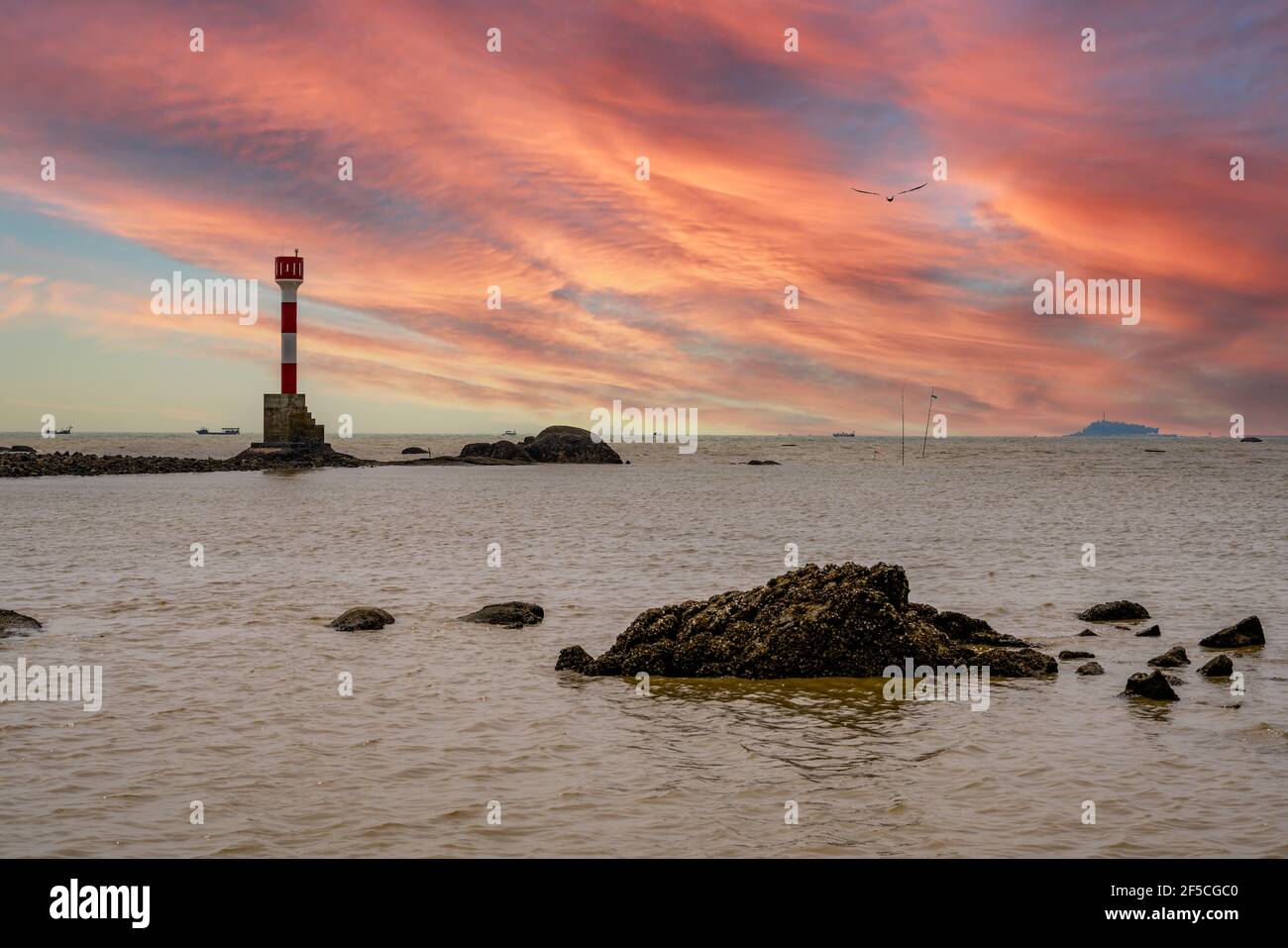 The beacon lighthouse under the gorgeous sunset by the sea Stock Photo ...