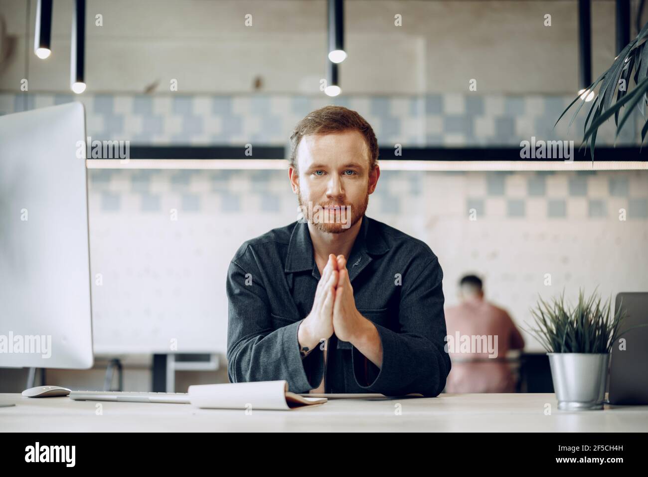 Young businessman sitting at working table in office and pondering ...