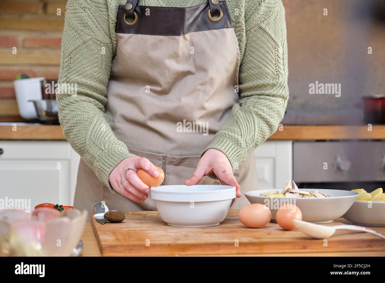 Unrecognizable young woman cracking or breaking an egg. Cooking time ...