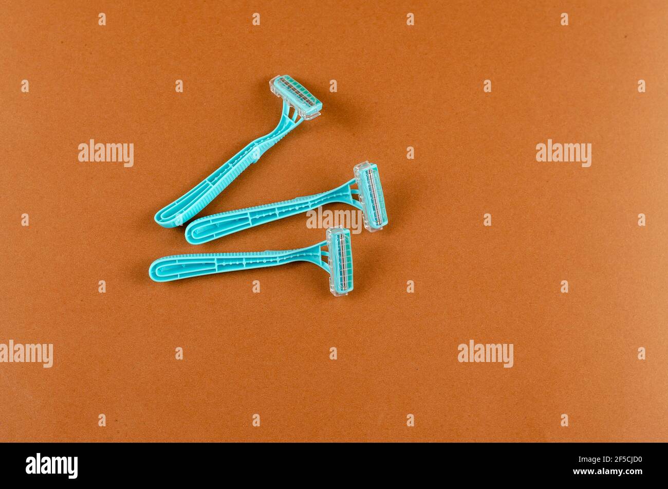 Blue plastic razors on a brown background. Three new razor. Top view ...
