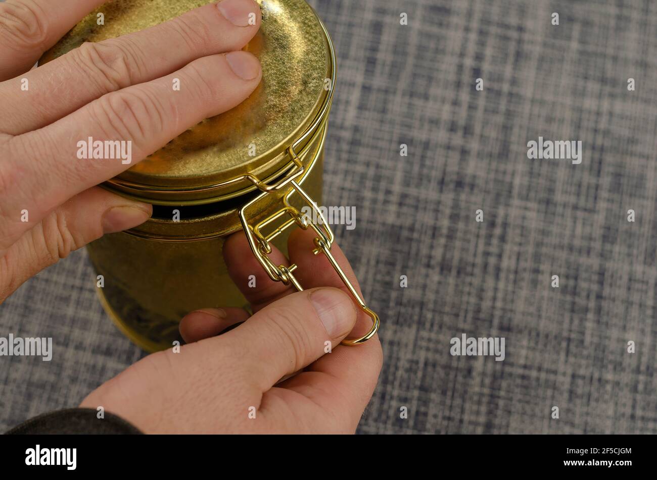 Man's hand opens Tea coffee tin with clasp close-up. Gold latch lock ...