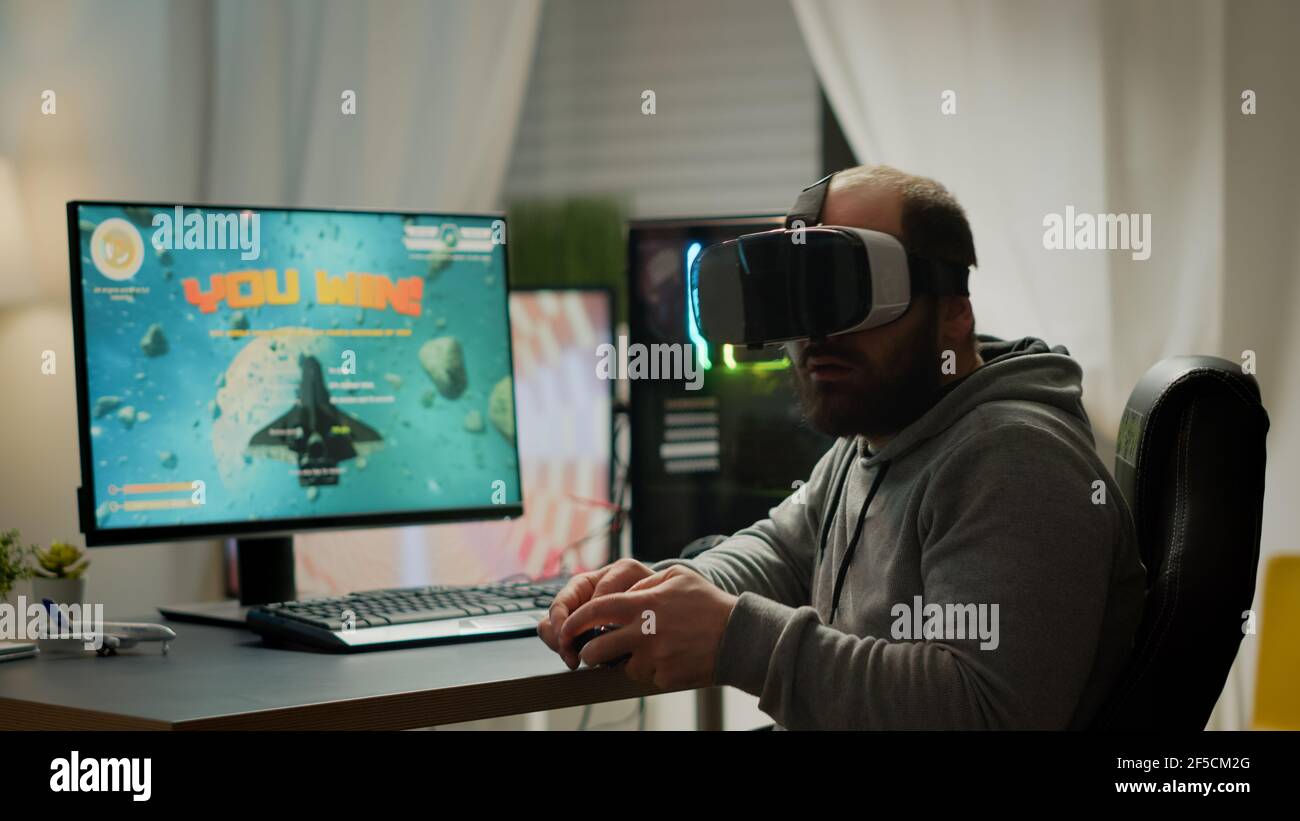 Videogame player with VR headset raising hands after winning space ...