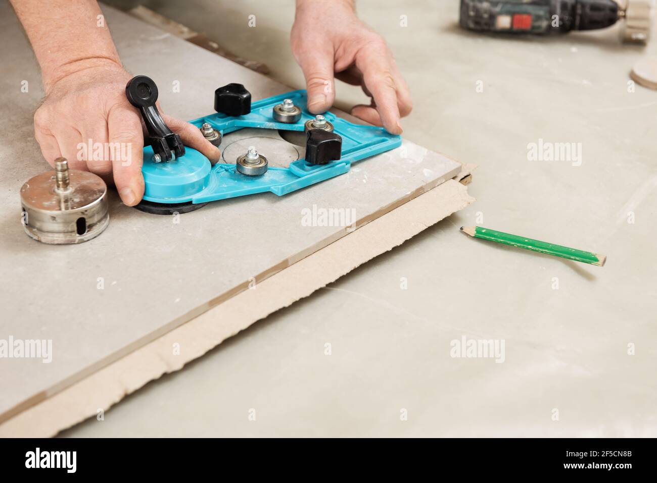 A tiler uses a caliper with a suction cup to drill holes in the ceramic ...