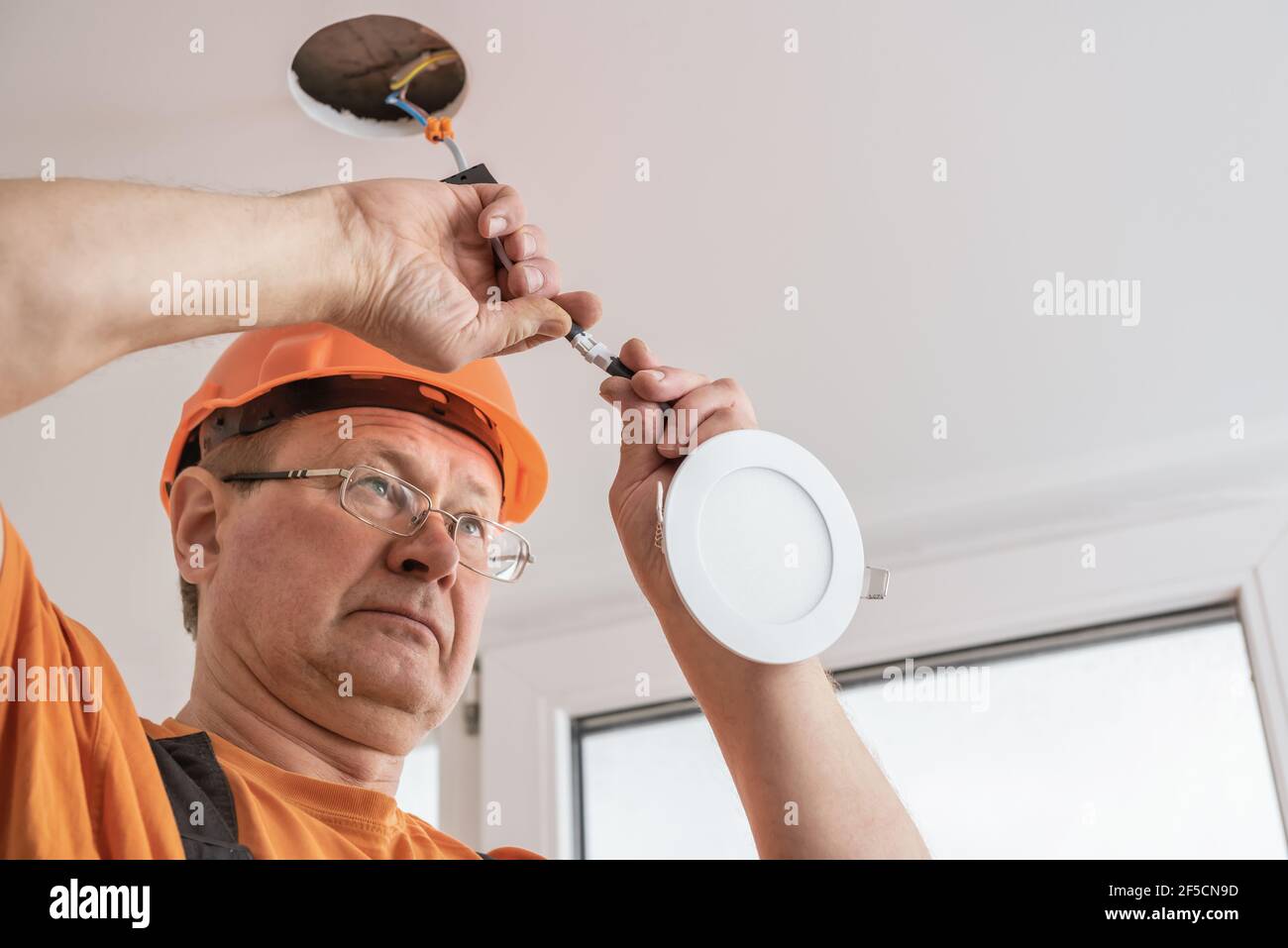 The electrician is installing an LED spotlight in the ceiling Stock ...