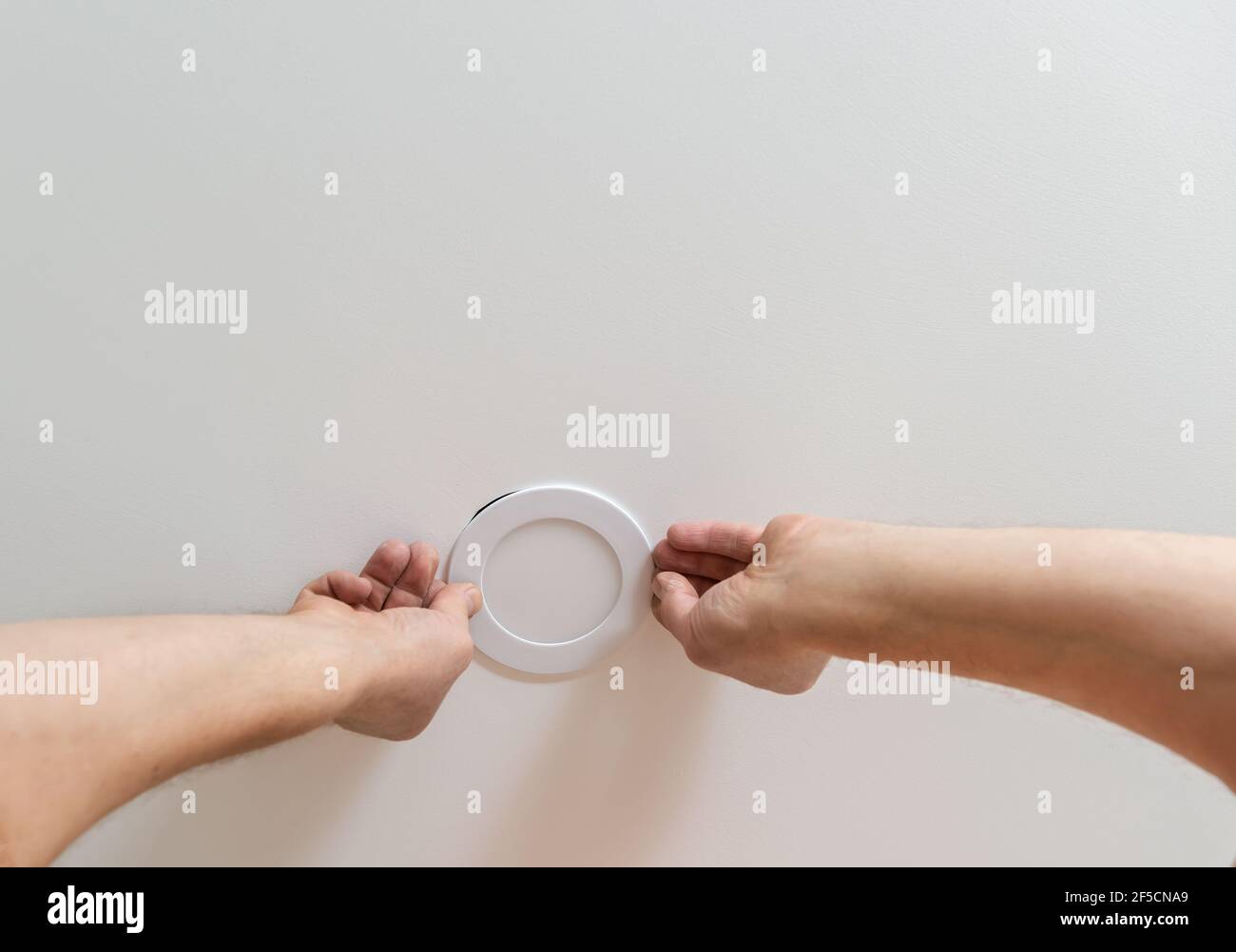 An electrician is installing an LED spotlight in the ceiling Stock ...