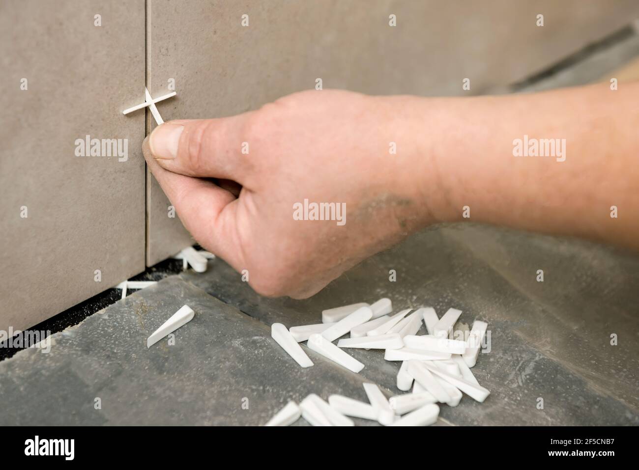 The tiler is installing plastic crosses in the seams of ceramic tiles ...