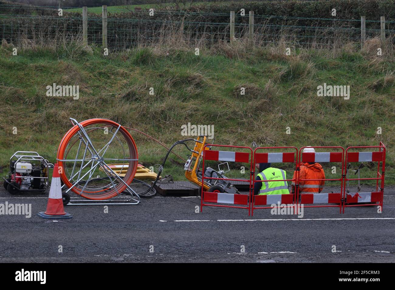 A reel of fiber-optic cable is fed into a manhole during the ...