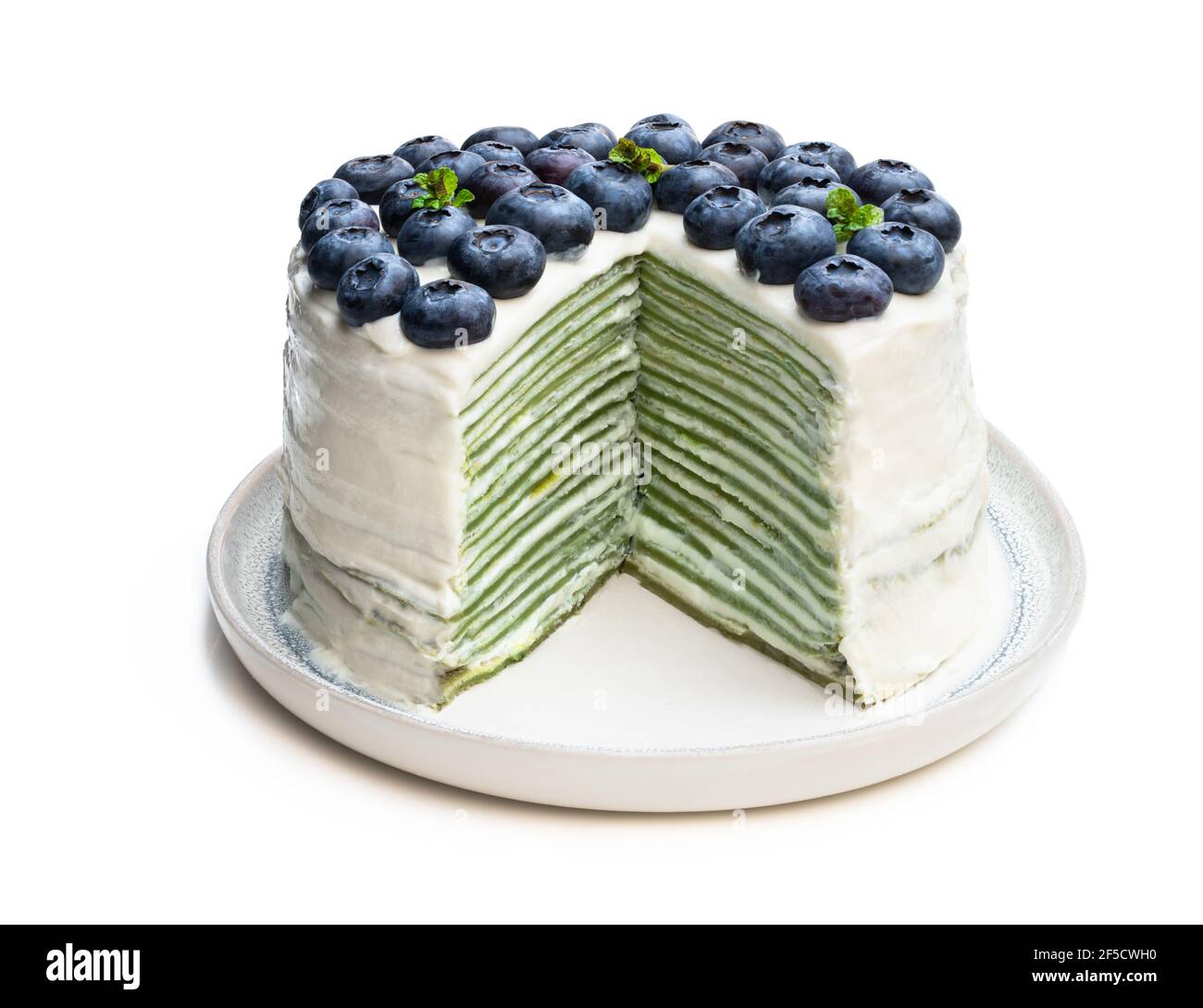 Layered matcha pancake cake with cream and blueberry isolated on white ...