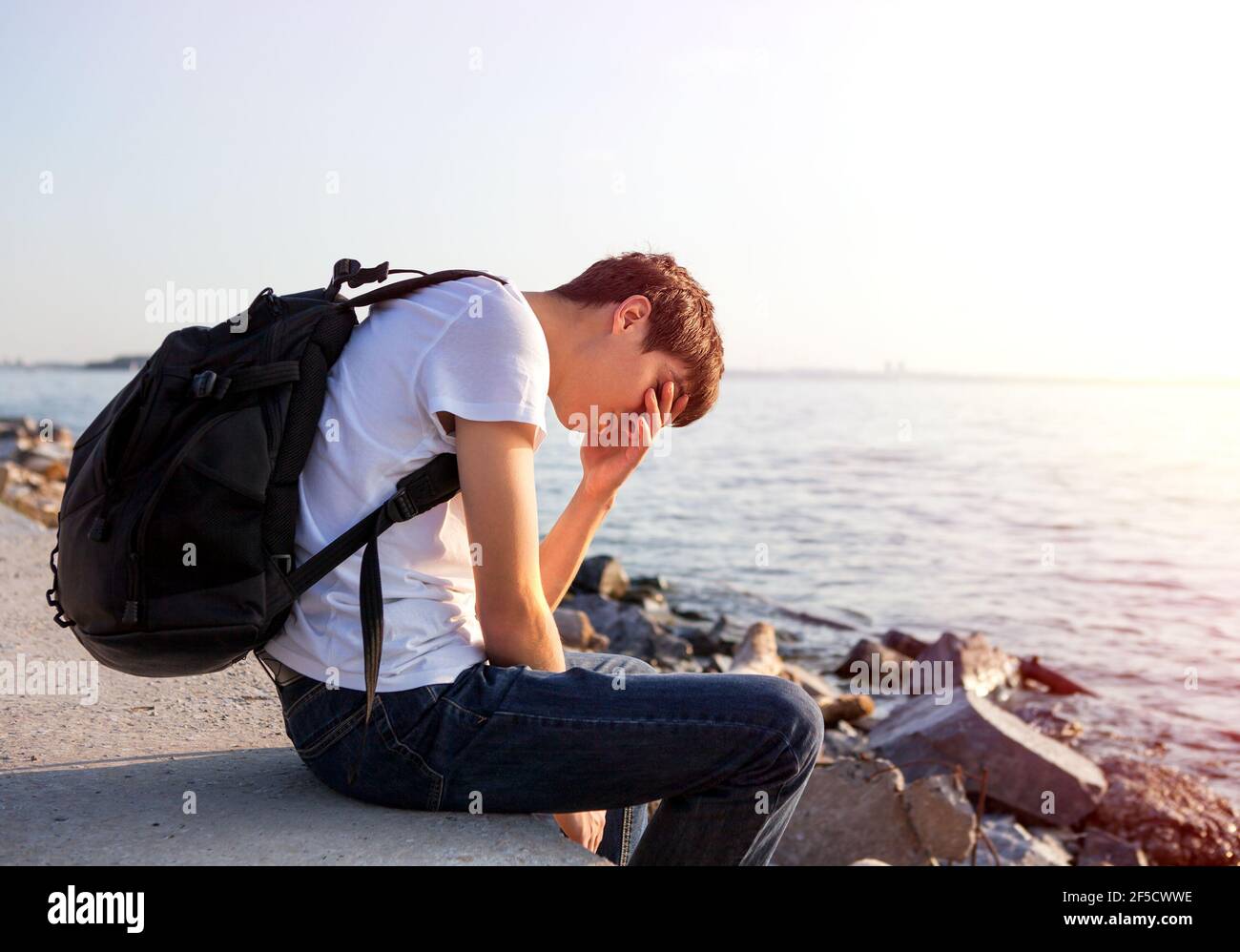 Sad Young Man with Backpack at the Seaside Stock Photo - Alamy
