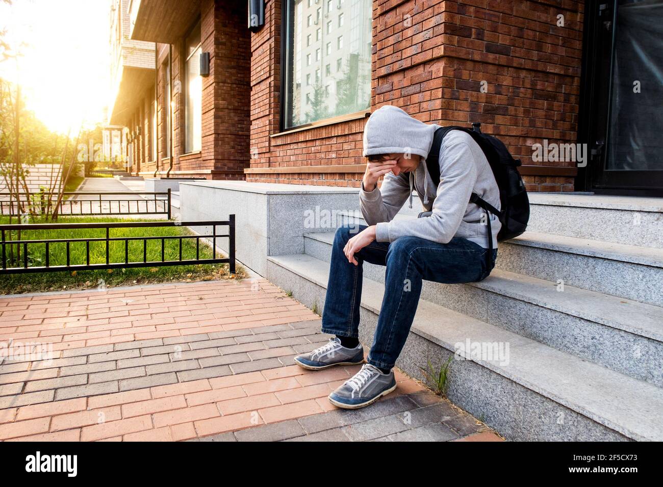 Sad Young Man sit on the City Street Stock Photo - Alamy
