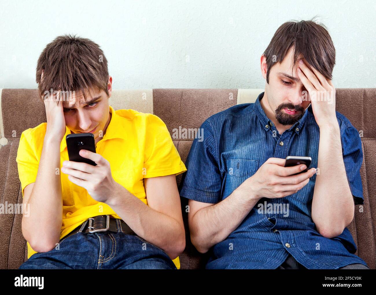 Two Sad Men with a Phones on the Couch in the Room Stock Photo - Alamy