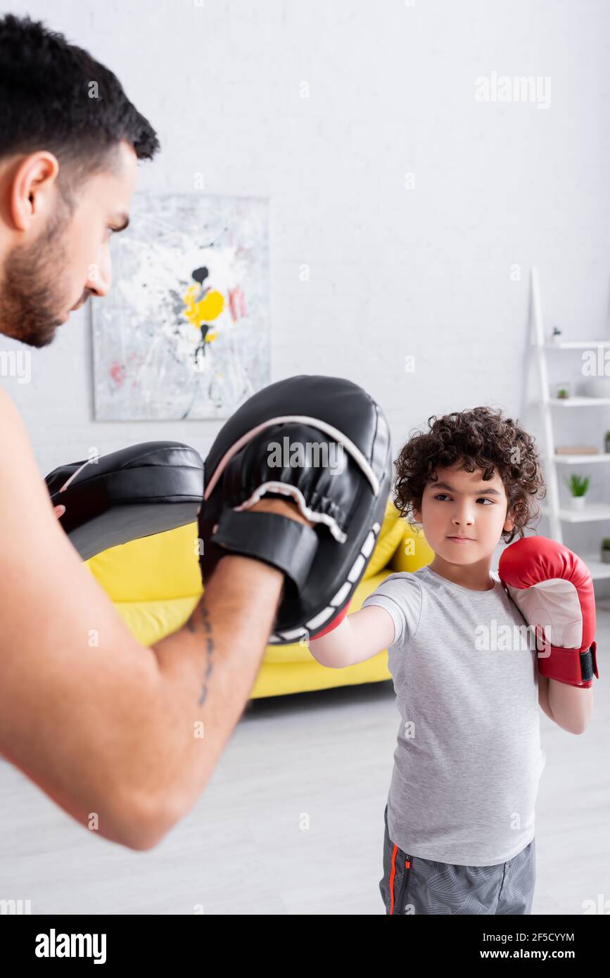 Muslim boy in boxing gloves boxing with father in punch mitts on ...