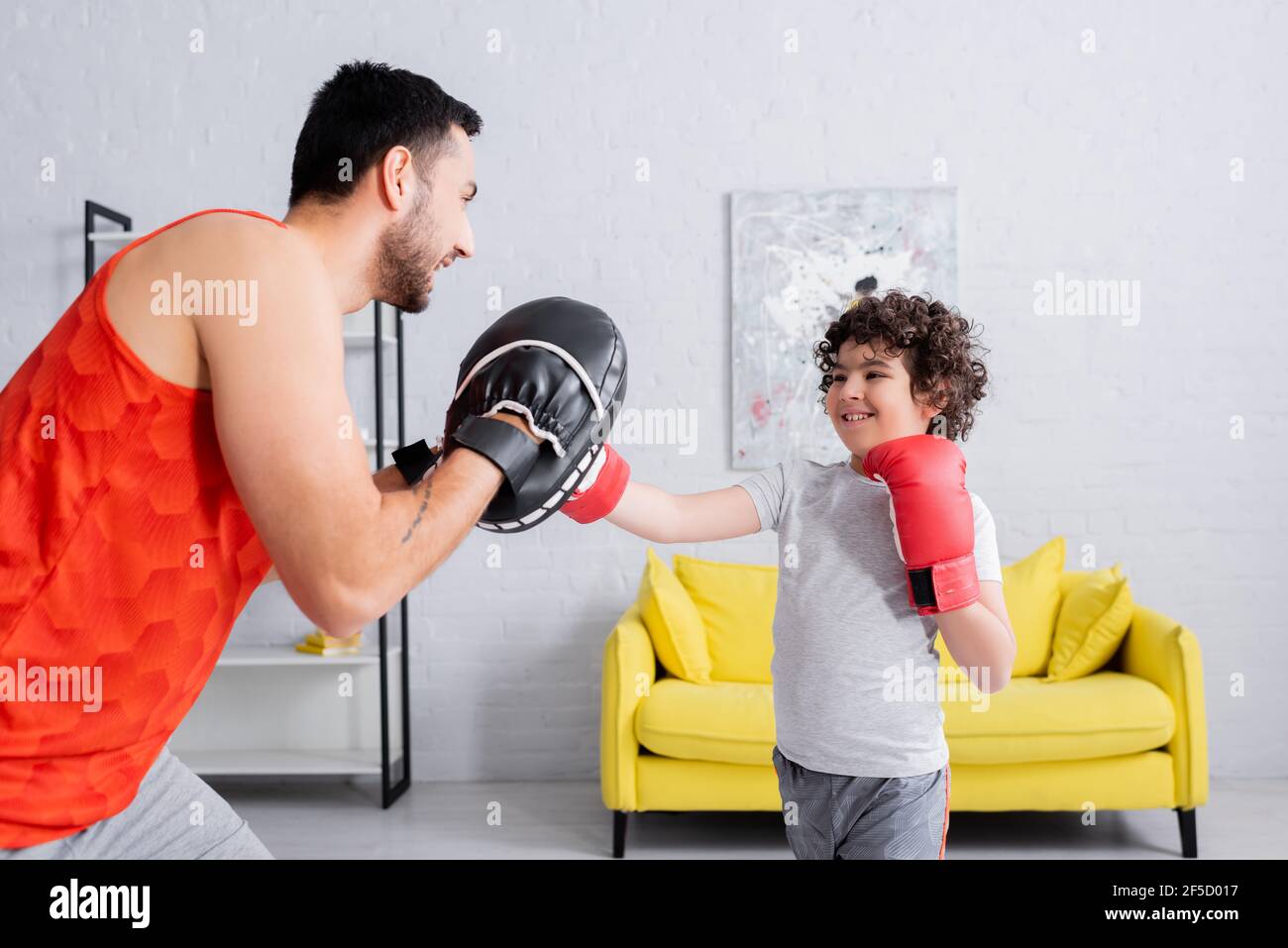 Cheerful muslim boy boxing with father at home Stock Photo - Alamy