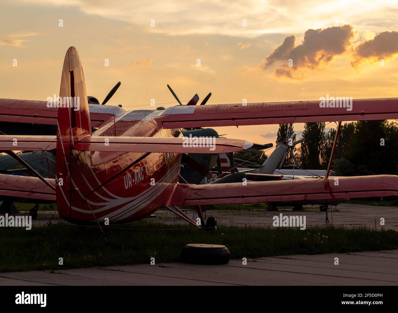 Part of the shiny hull of a red small-passenger plane in sunset light ...
