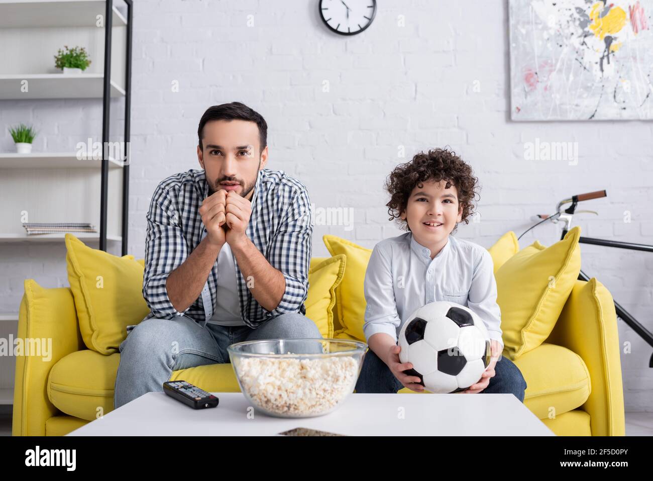 Arabian Father And Preteen Son With Football Watching Match Near