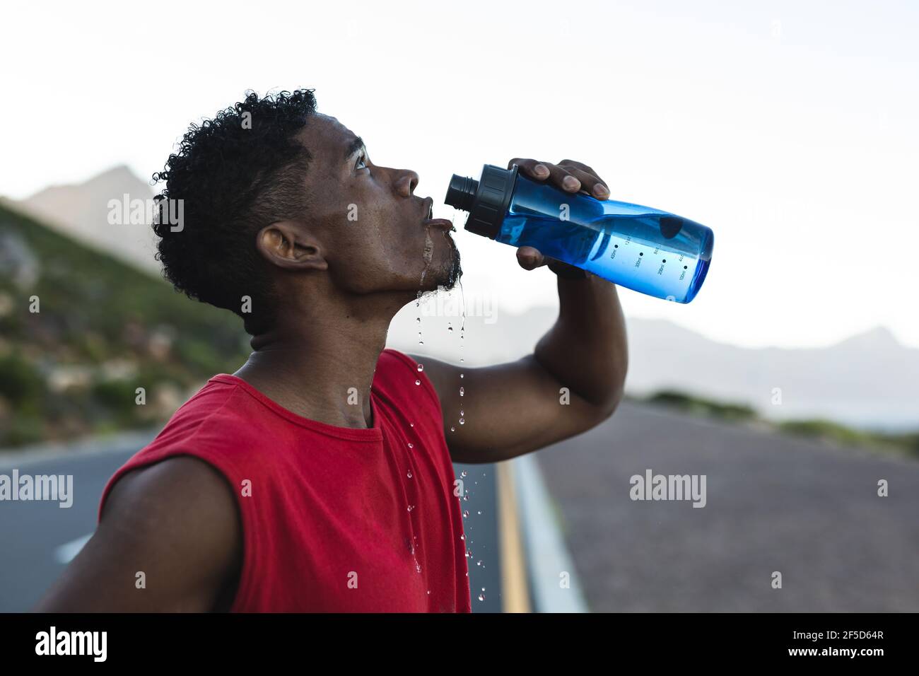 African american man exercising outdoors drinking water on a coastal ...