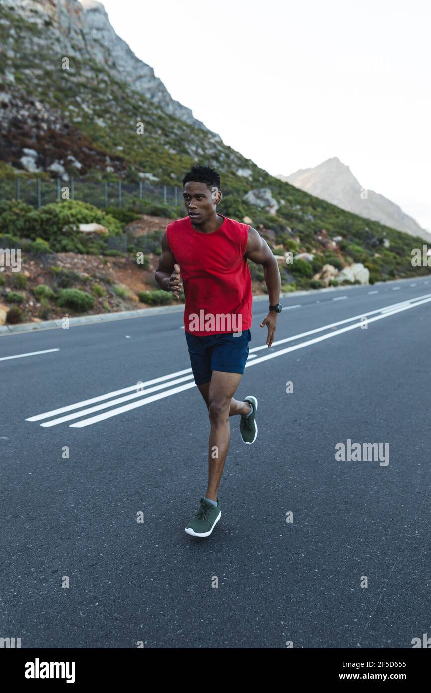 African american man exercising outdoors running on a coastal road ...