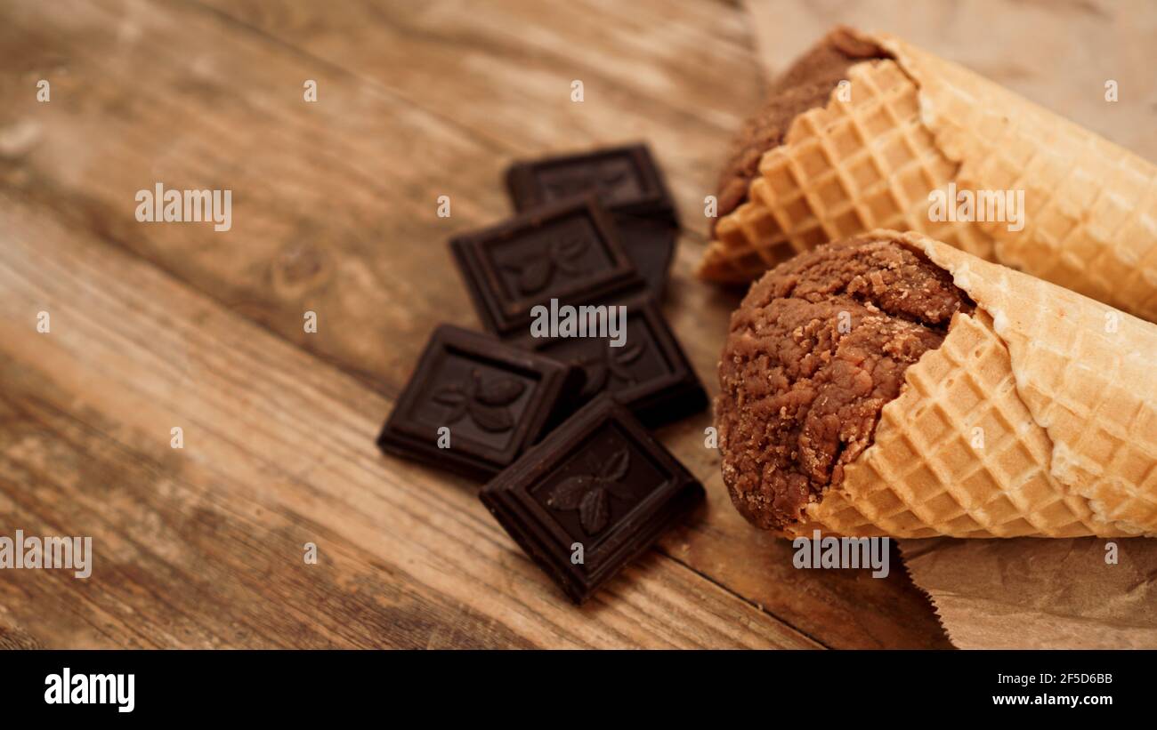 Chocolate ice cream in a waffle cone on craft paper on a wooden ...